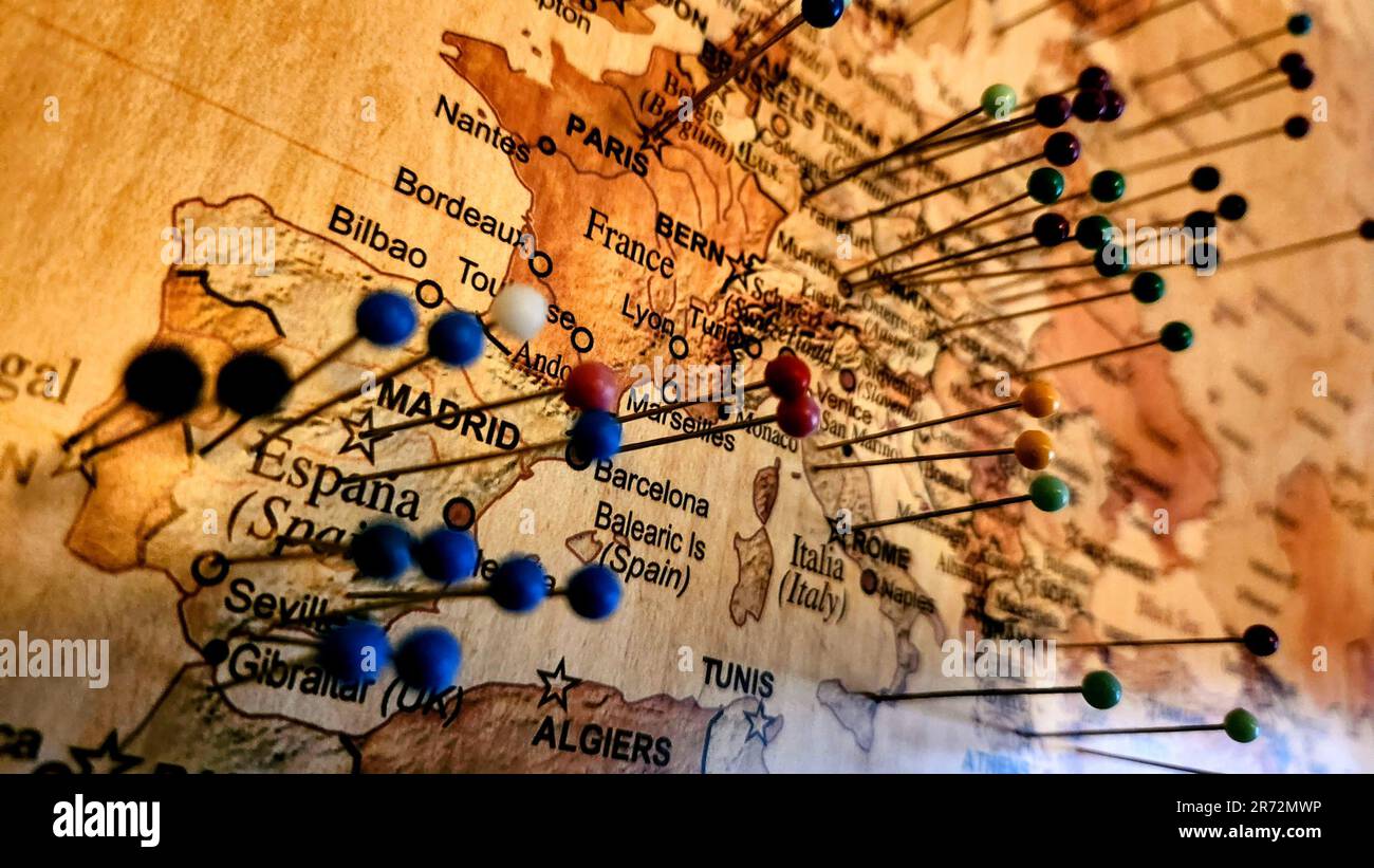 A wall with a large world map and several colorful pins inserted into ...