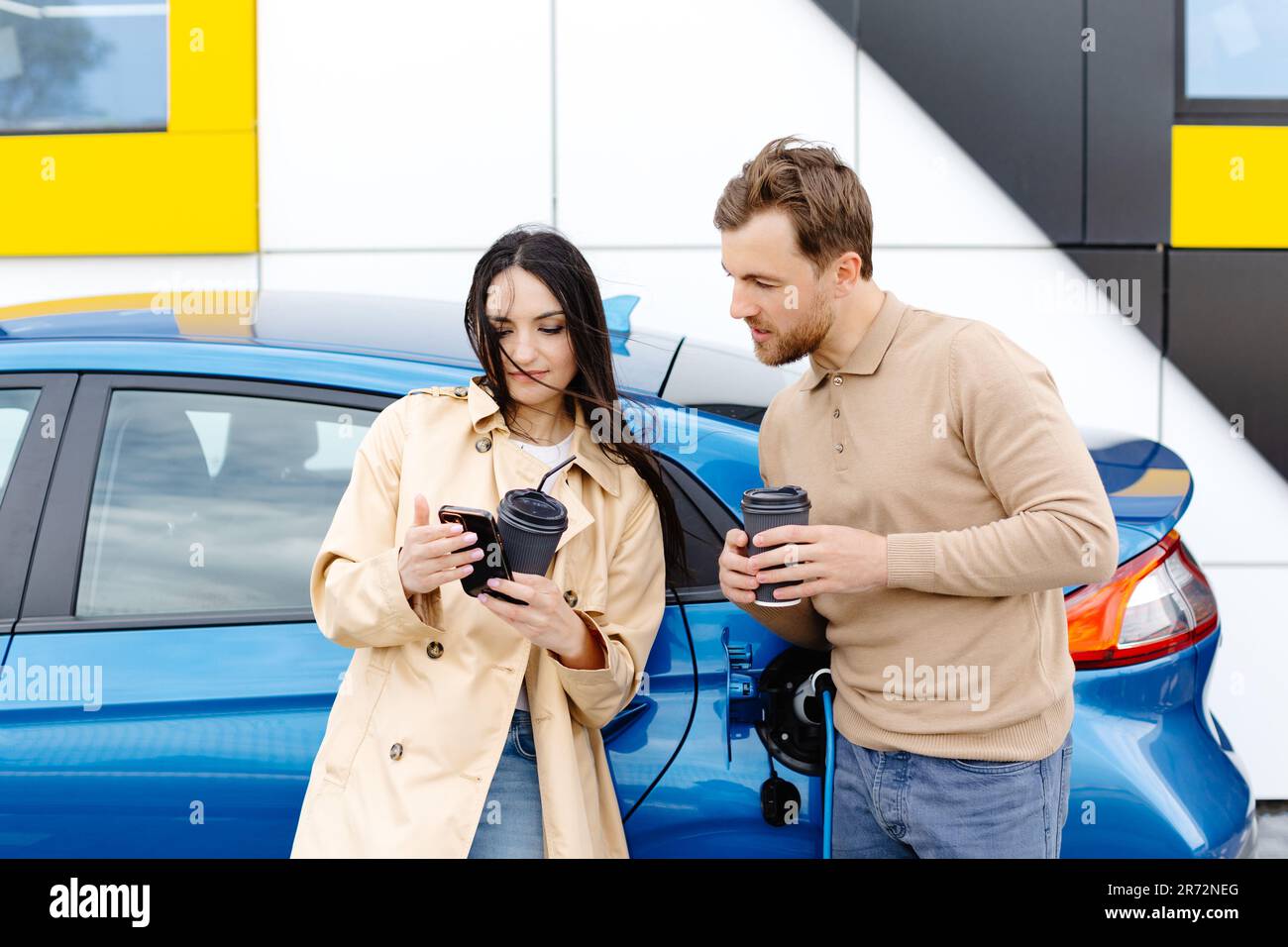 Young couple man and woman traveling by electric car having stop at ...