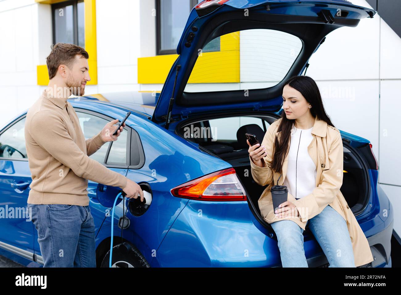 Young couple man and woman traveling by electric car having stop at ...