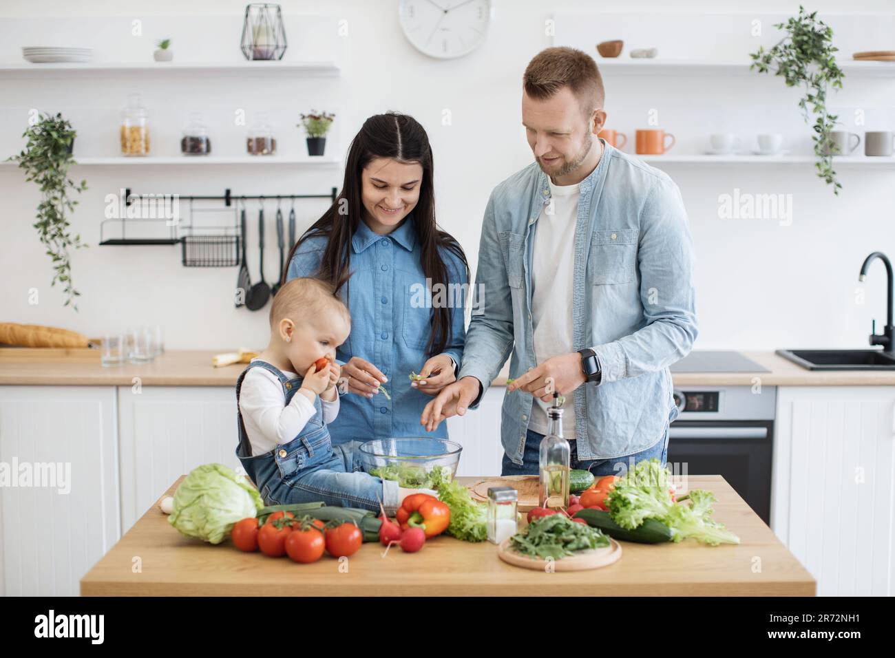 Amusing little child in denim clothes savouring juicy tomato while ...