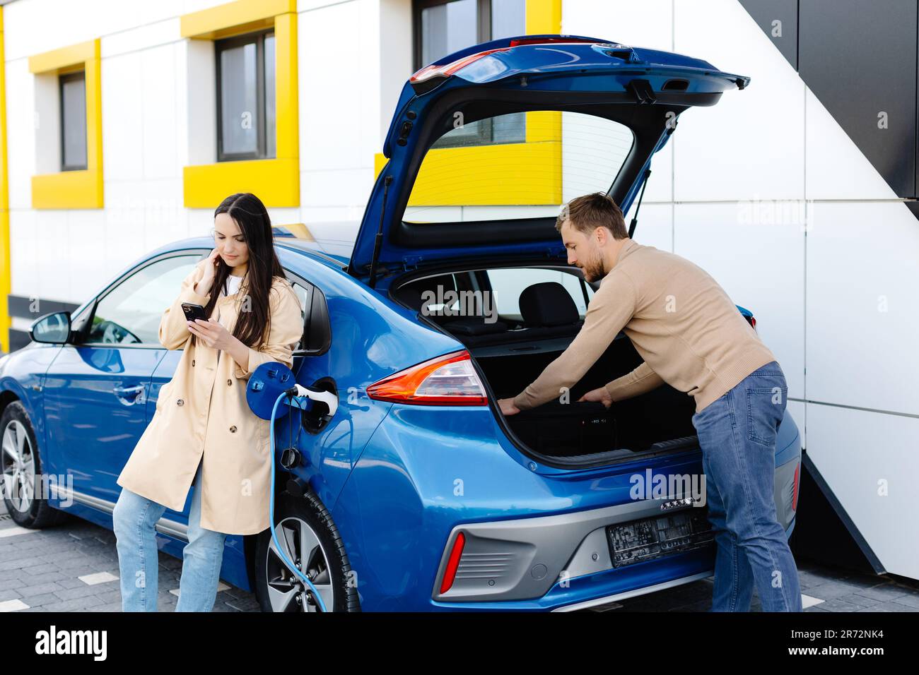 Young couple man and woman traveling by electric car having stop at ...