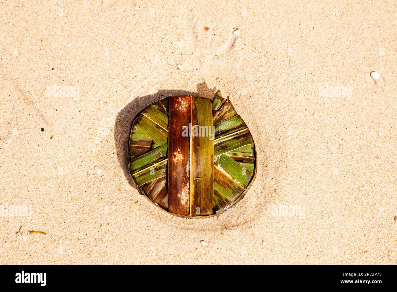Handmade beach paraphernalia made from banana leaves on a sandy beach ...