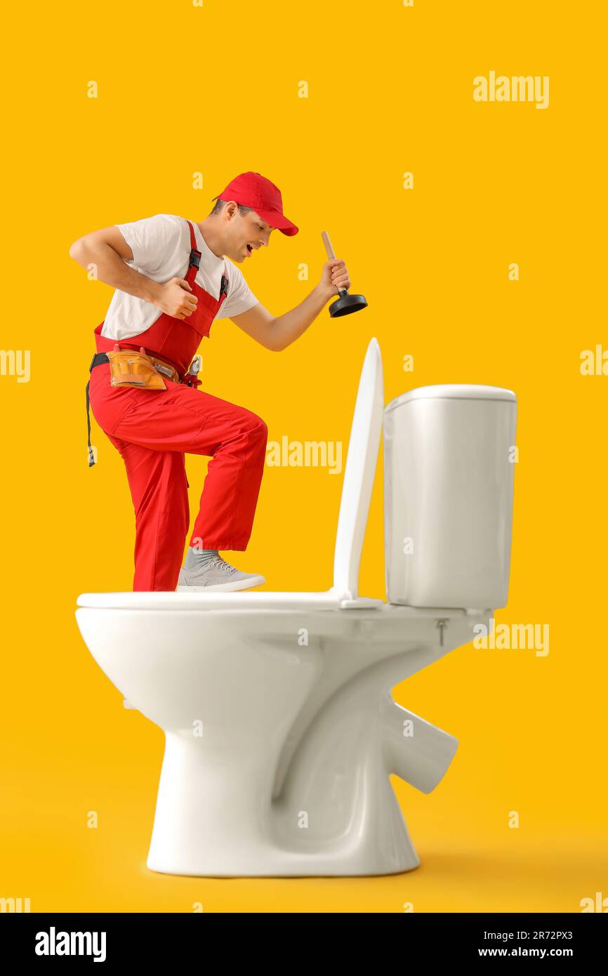 Young plumber with plunger and toilet bowl on yellow background Stock ...