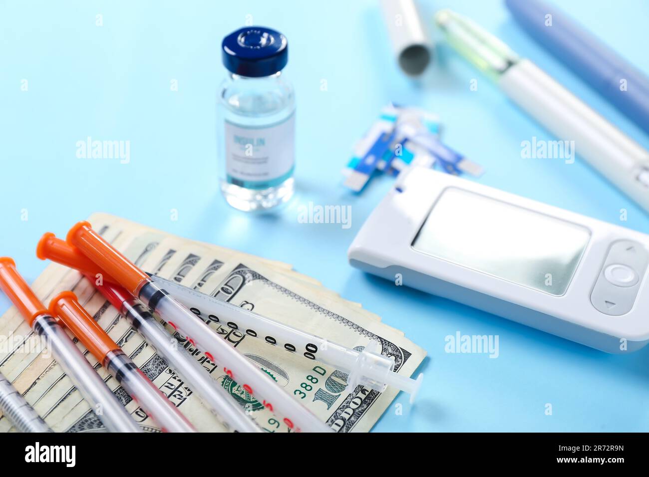 Syringes with money, glucometer and insulin on blue background, closeup ...