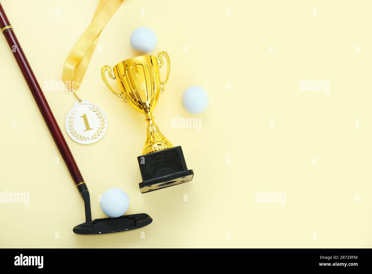 Gold cup with first place medal, golf club and balls on yellow ...
