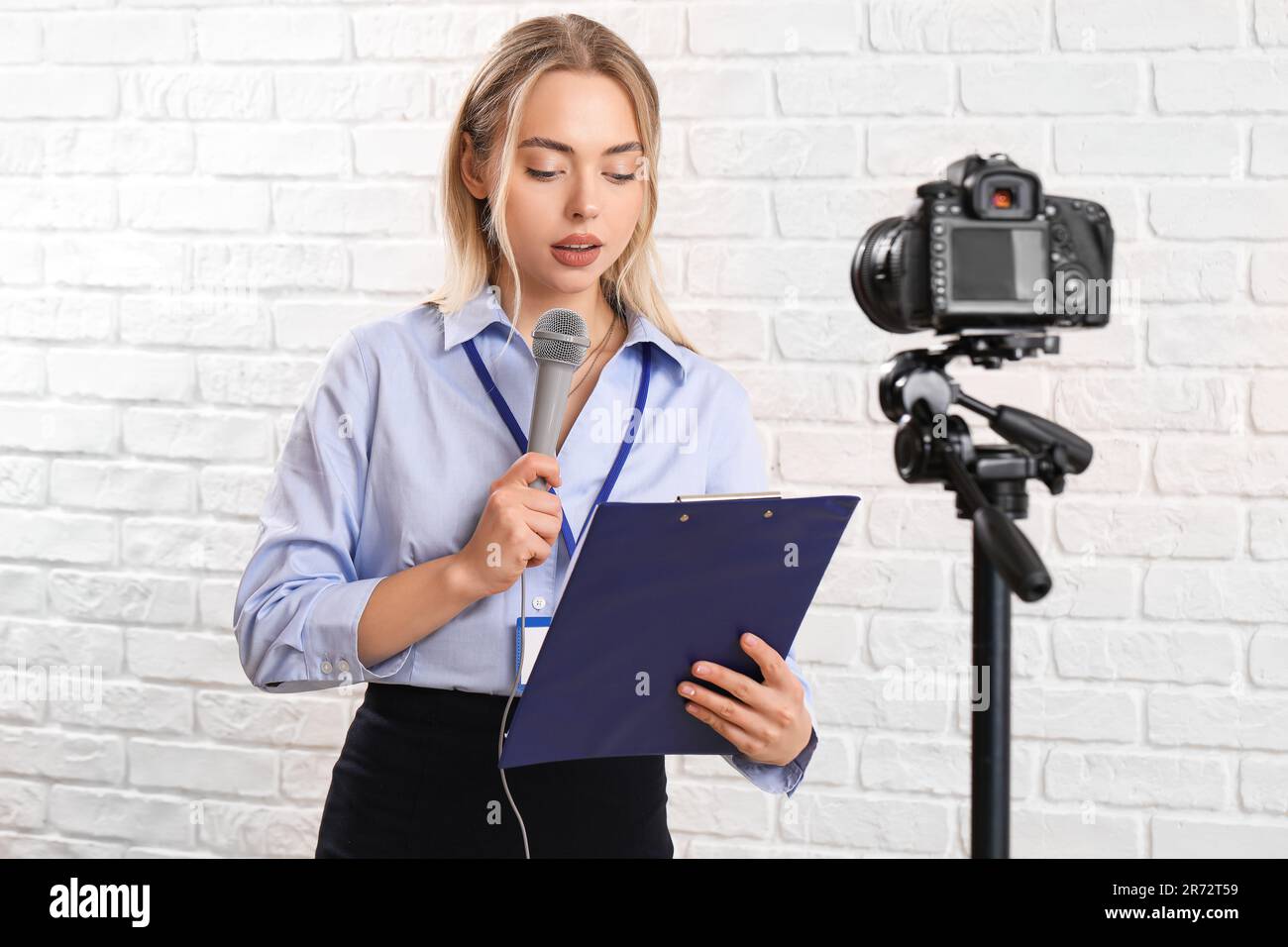 Female journalist with microphone and clipboard recording video on ...