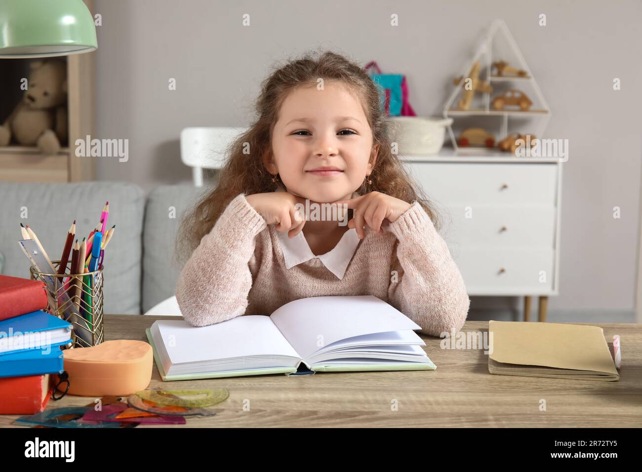 Cute little girl reading book at home Stock Photo - Alamy