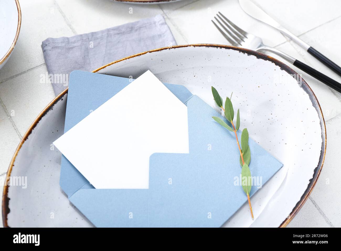 Stylish table setting, envelope with blank card and plant branch on ...
