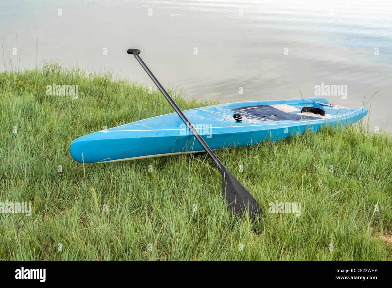 touring stand up paddleboard with a paddle on a grassy lake shore Stock ...