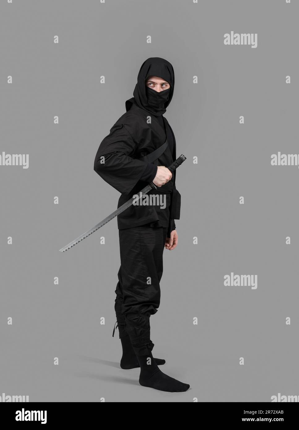 Male ninja with sword on grey background Stock Photo - Alamy