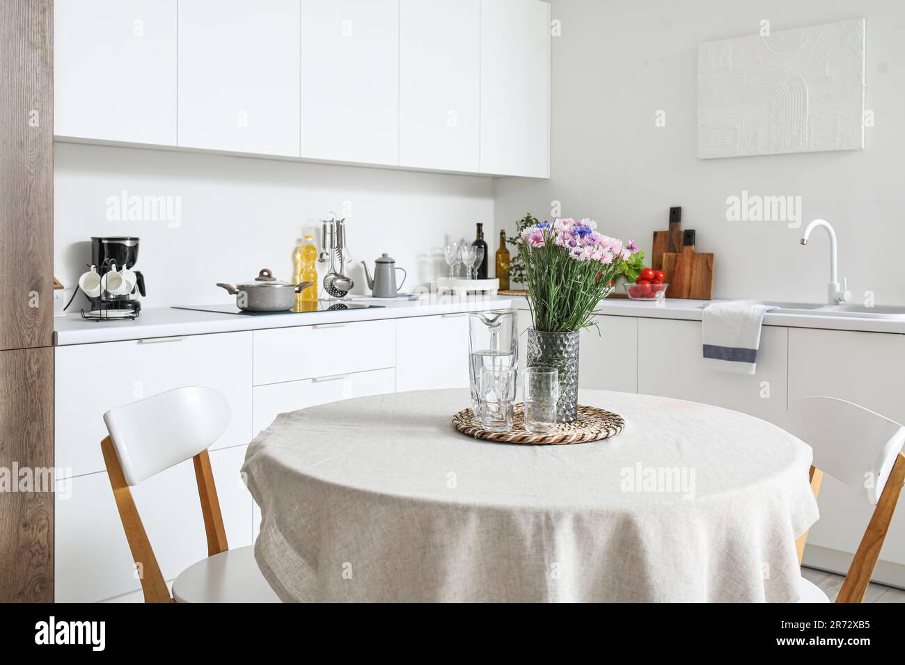 Interior of modern kitchen with flowers on dining table Stock Photo - Alamy