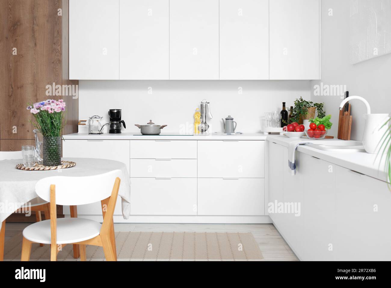 Interior of modern kitchen with flowers on dining table Stock Photo - Alamy