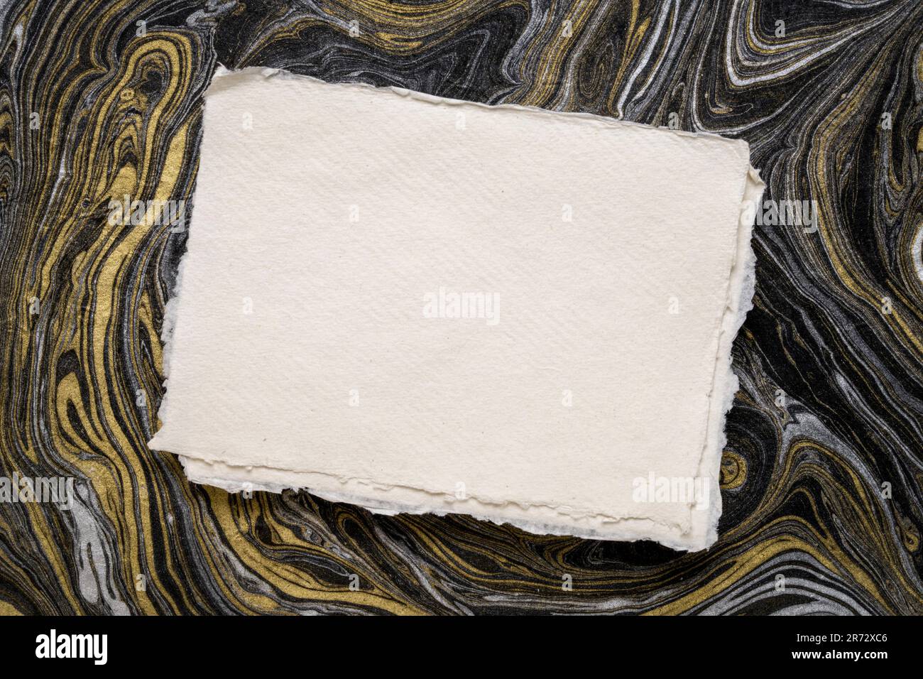 sheet of blank white Khadi rag paper against abstract black and gold ...