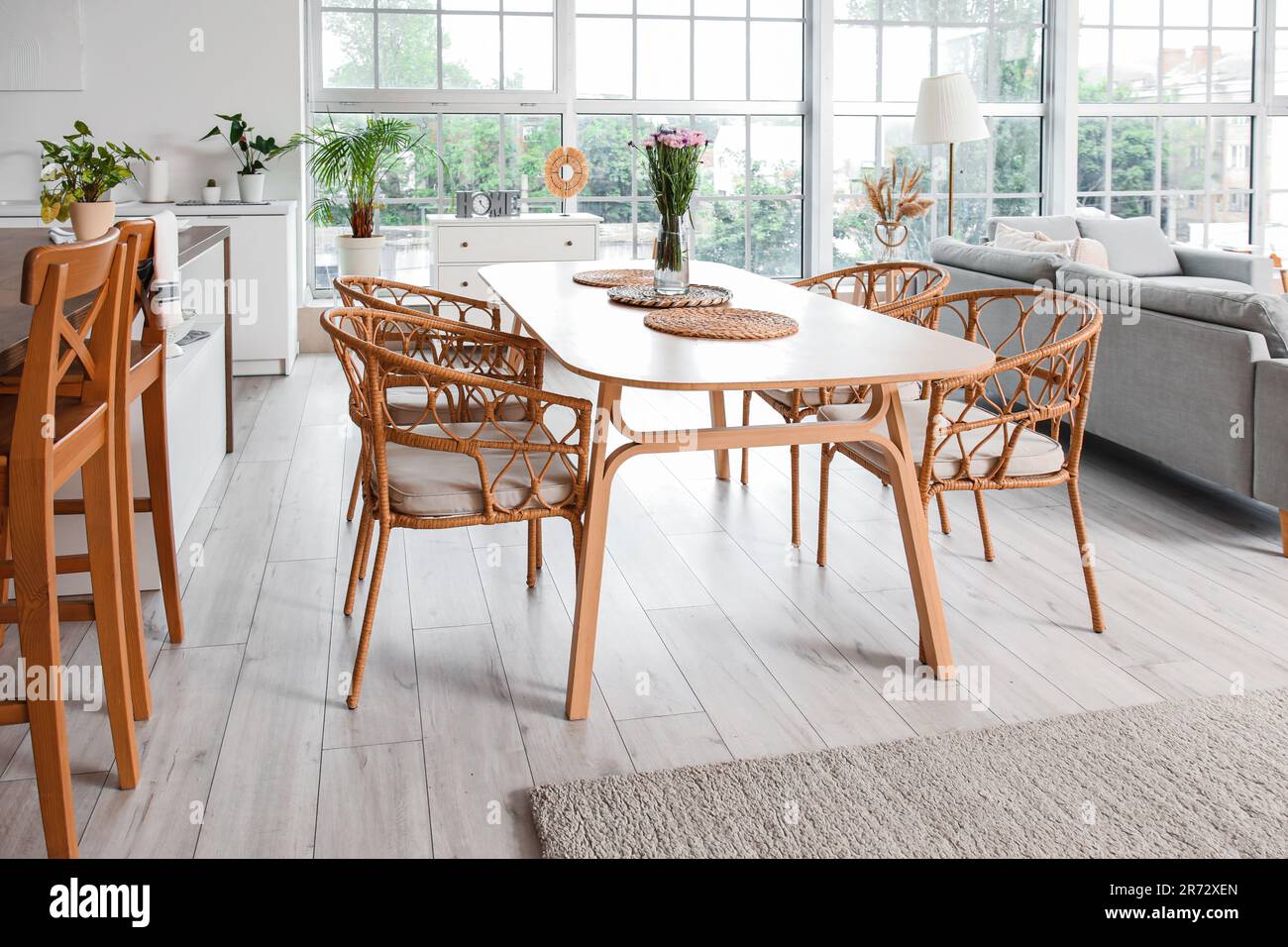 Interior of light open plan kitchen with dining table and grey sofa ...