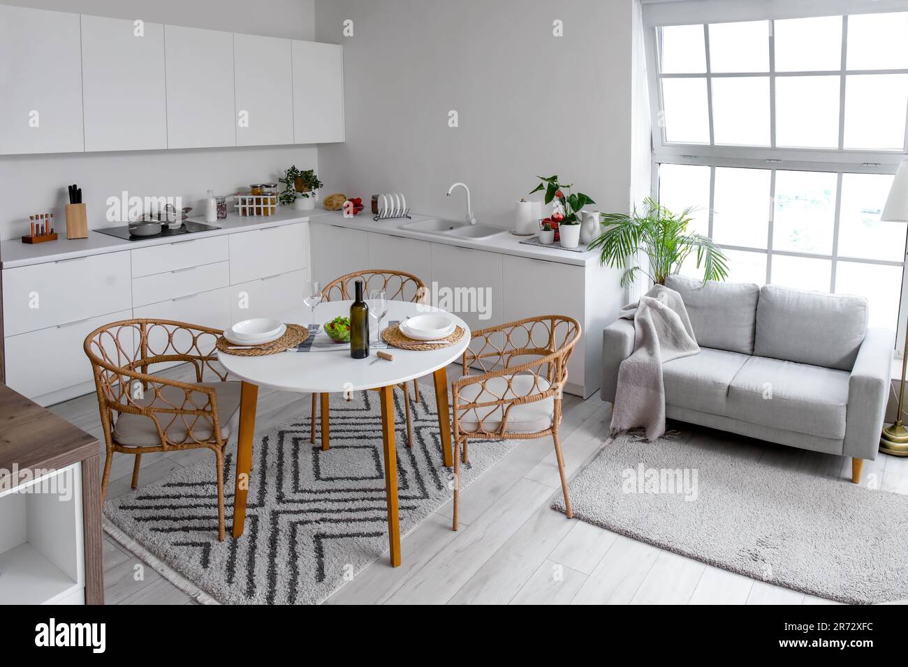 Interior of light open plan kitchen with served dining table and grey ...
