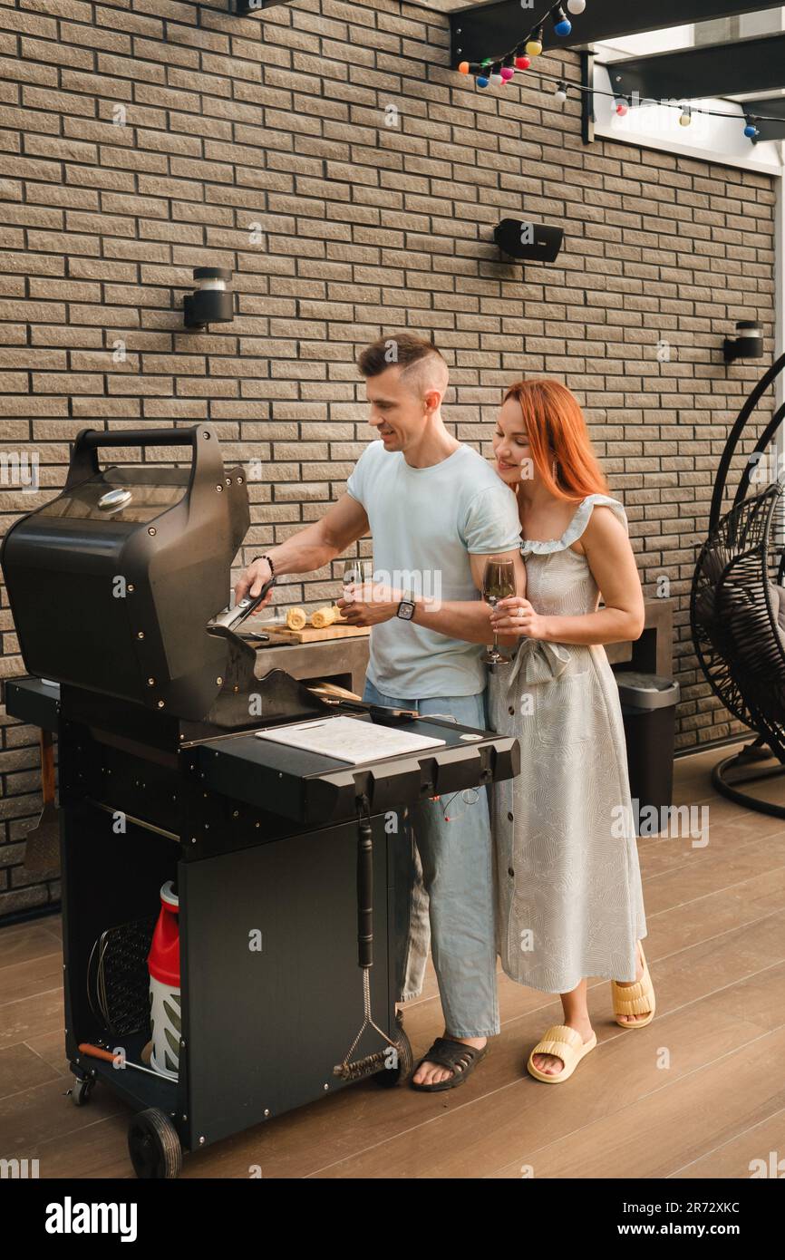 A married couple cooks grilled meat together on their terrace Stock ...