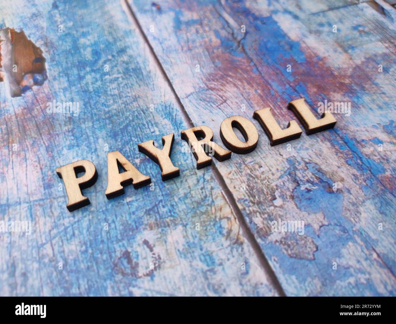 Wooden letters spelling out the word PAYROLL on a weathered blue wood ...