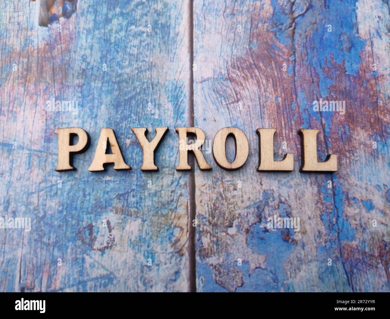 Wooden letters spelling out the word PAYROLL on a weathered blue wood ...