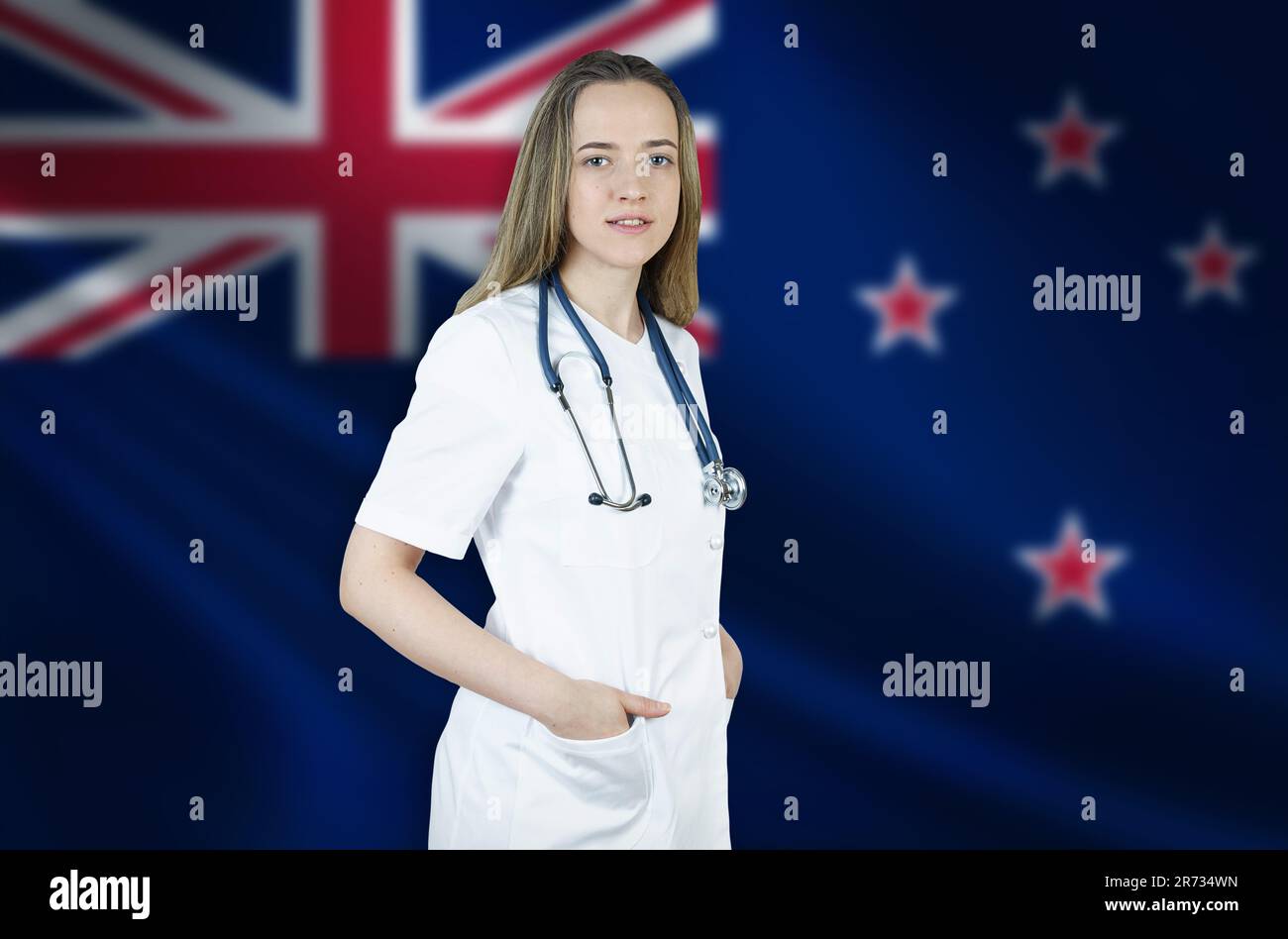 A young female doctor in a white coat and a stethoscope stands on the ...