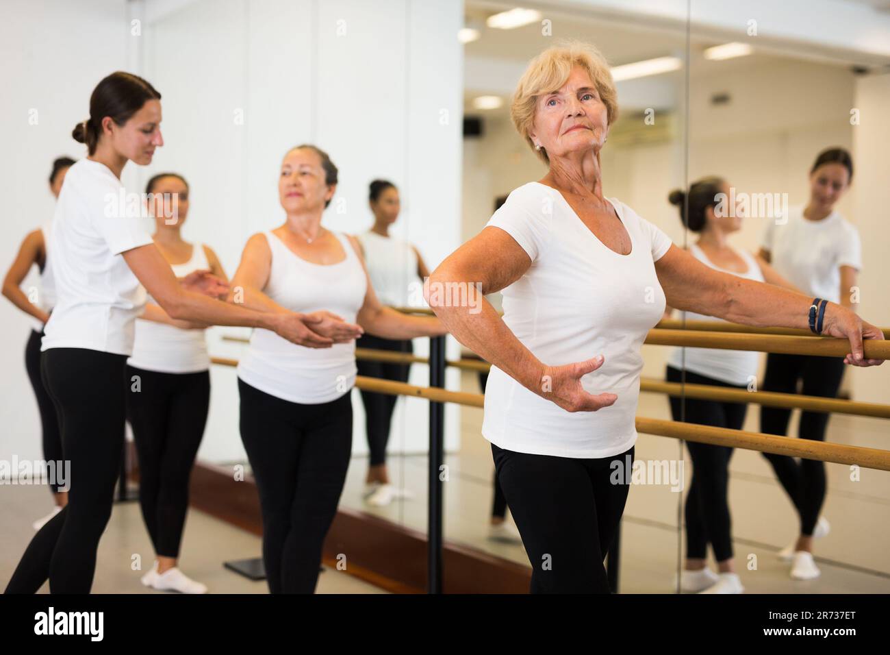 Dancing women stand in a ballet stance, where the choreographer helps ...