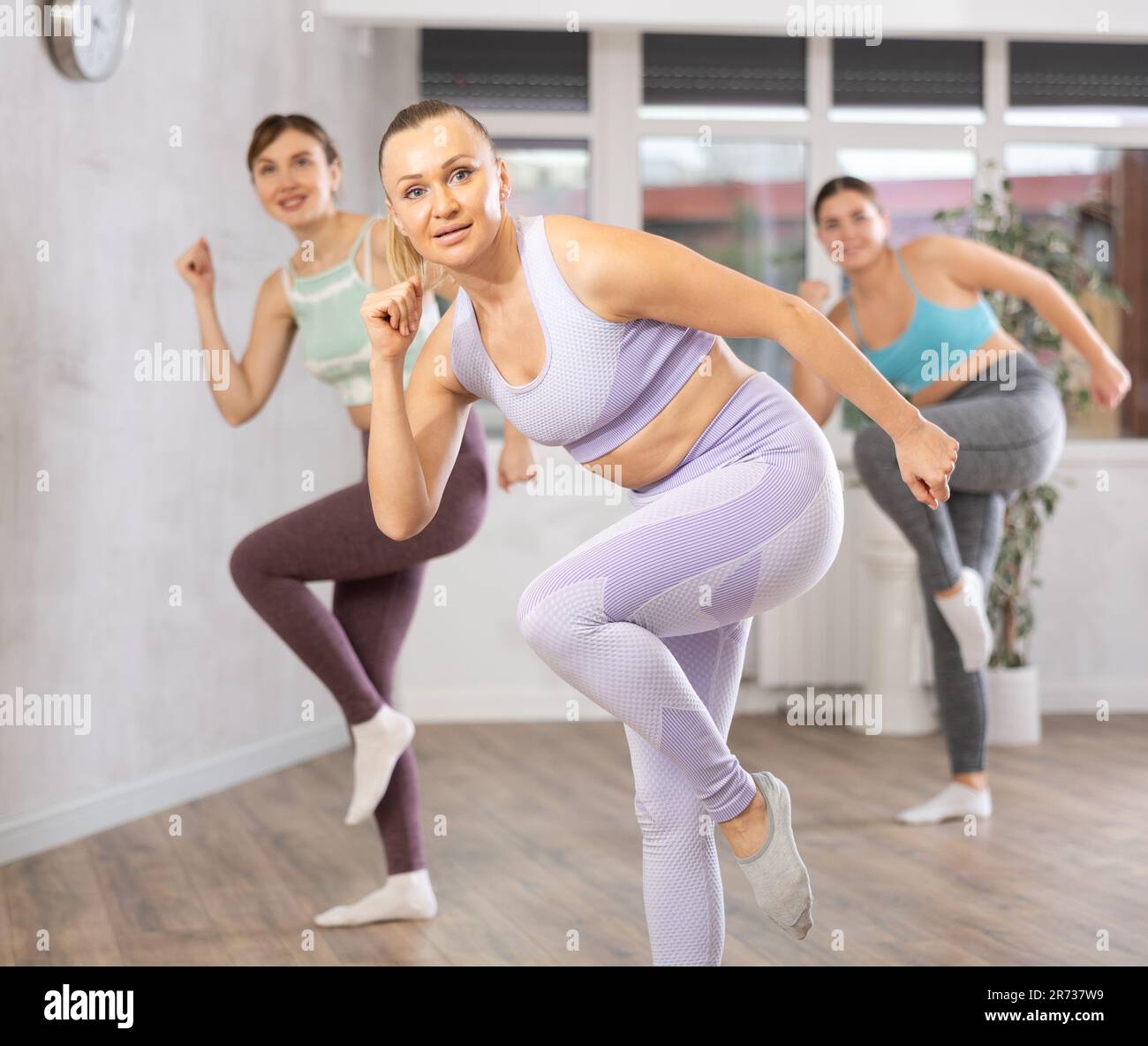 Group of active women practicing energetic dance in modern dance studio ...