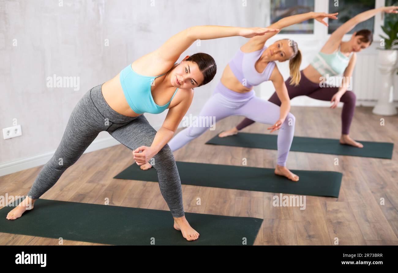 Class of motivated fit young women stretching in Extended Side Angle ...