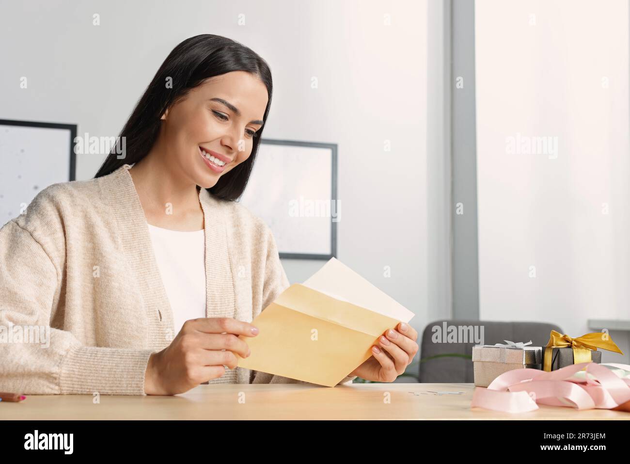 Happy woman reading greeting card at wooden table in room Stock Photo ...
