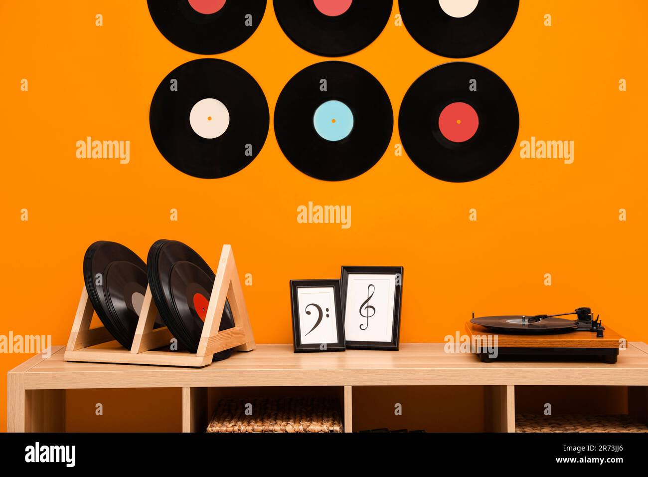 Vinyl records and player on wooden cabinet near orange wall Stock Photo ...