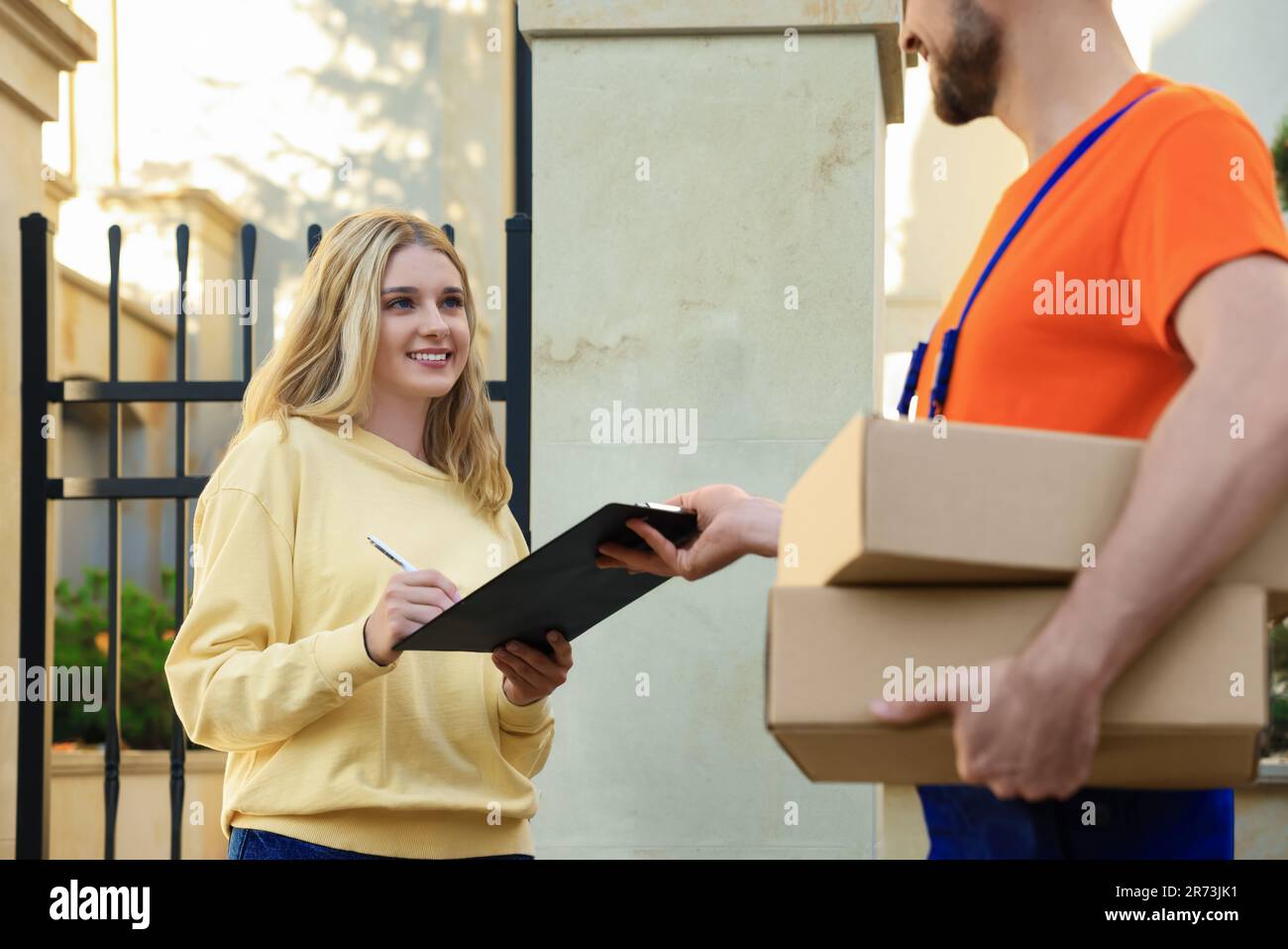 Woman signing order receipt outdoors. Courier delivery Stock Photo - Alamy
