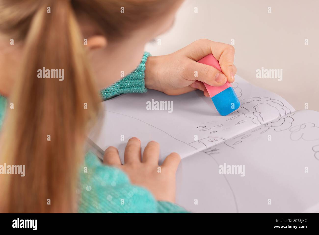 Girl erasing drawing in her book at white desk, closeup Stock Photo - Alamy