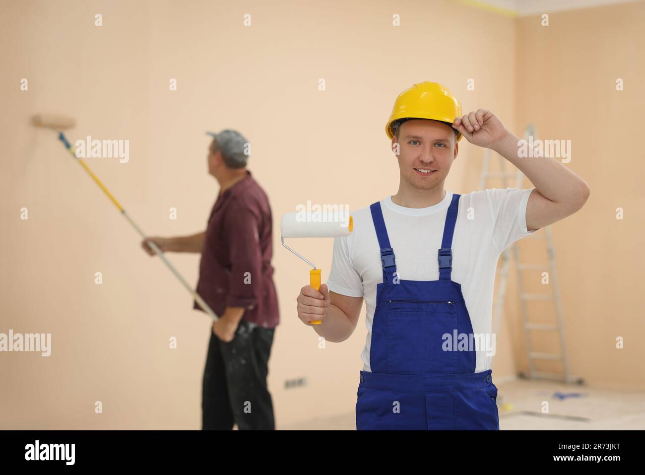 Worker holding paint roller in unfinished room. Painting walls Stock ...