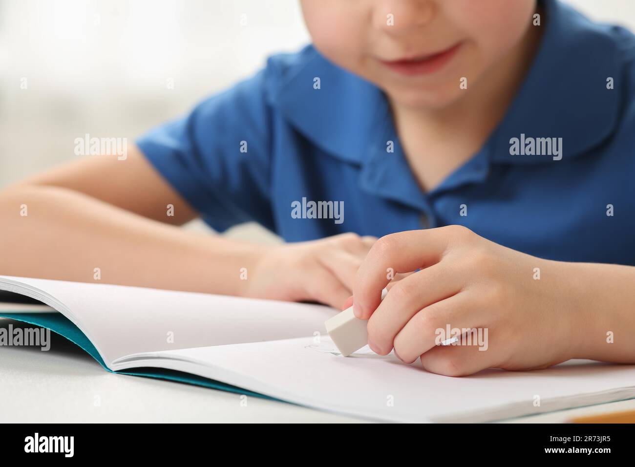 Little boy erasing mistake in his notebook at white desk, closeup Stock ...