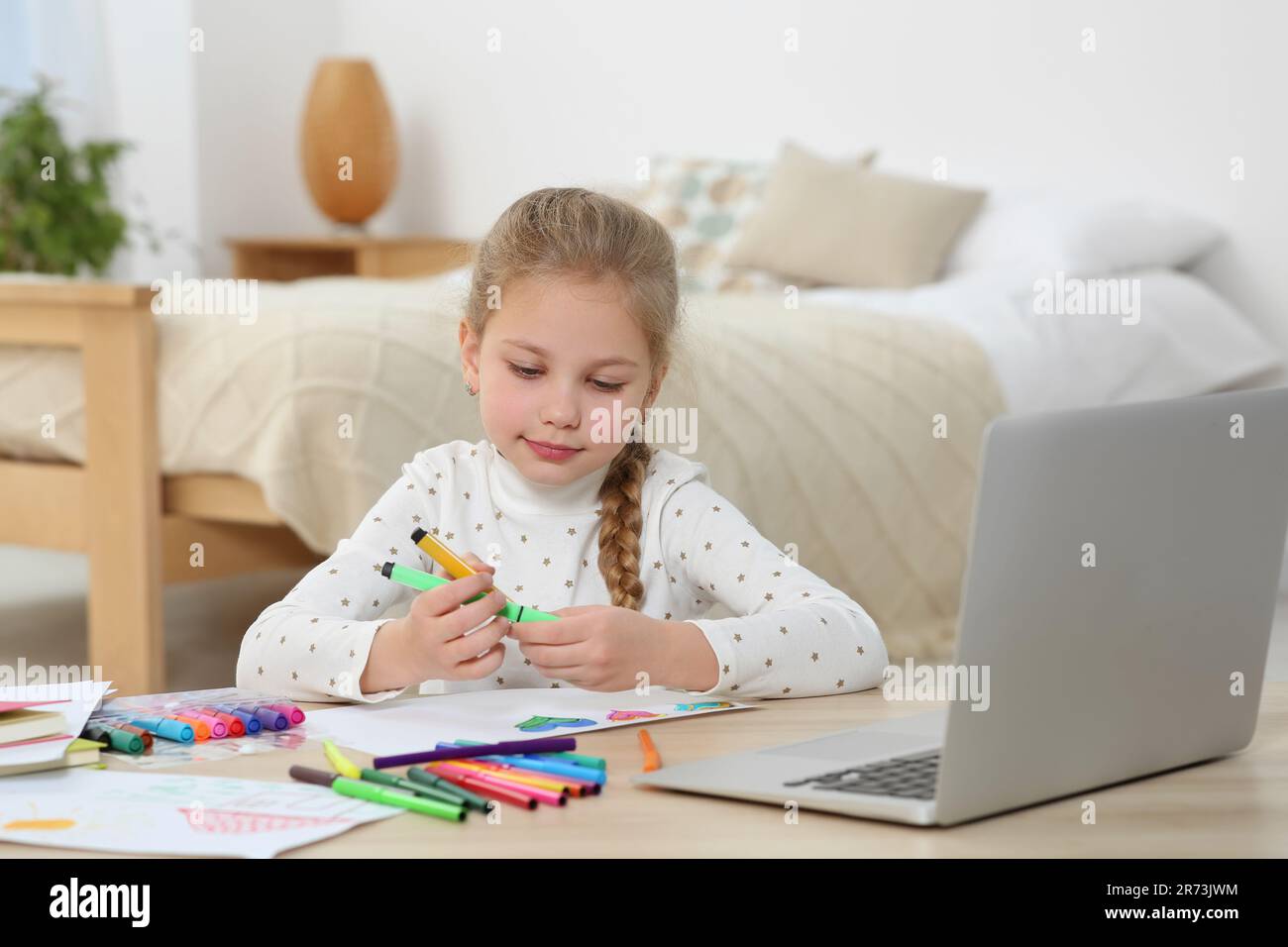 Little girl drawing with felt-tip pen following online course at home ...