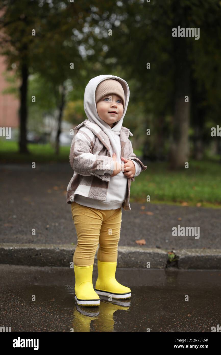 Cute little girl standing in puddle outdoors Stock Photo - Alamy