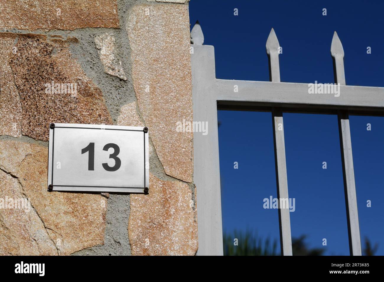 Plate with number 13 on textured stone wall near metal fence Stock ...