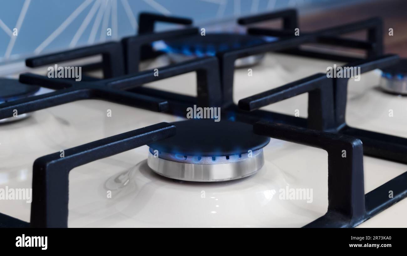 Gas cooktop with burning blue flames in kitchen, closeup. Cooking ...