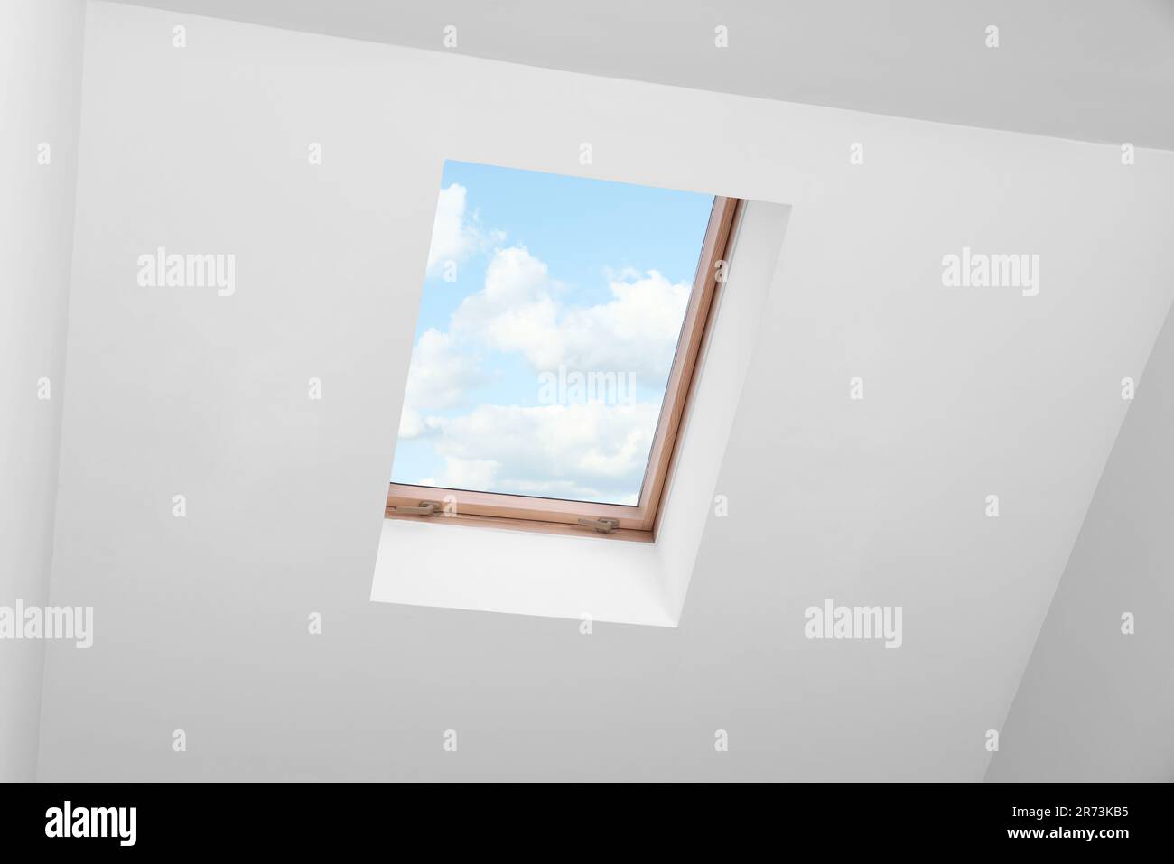 Skylight roof window and lamps on slanted ceiling in attic room, low ...