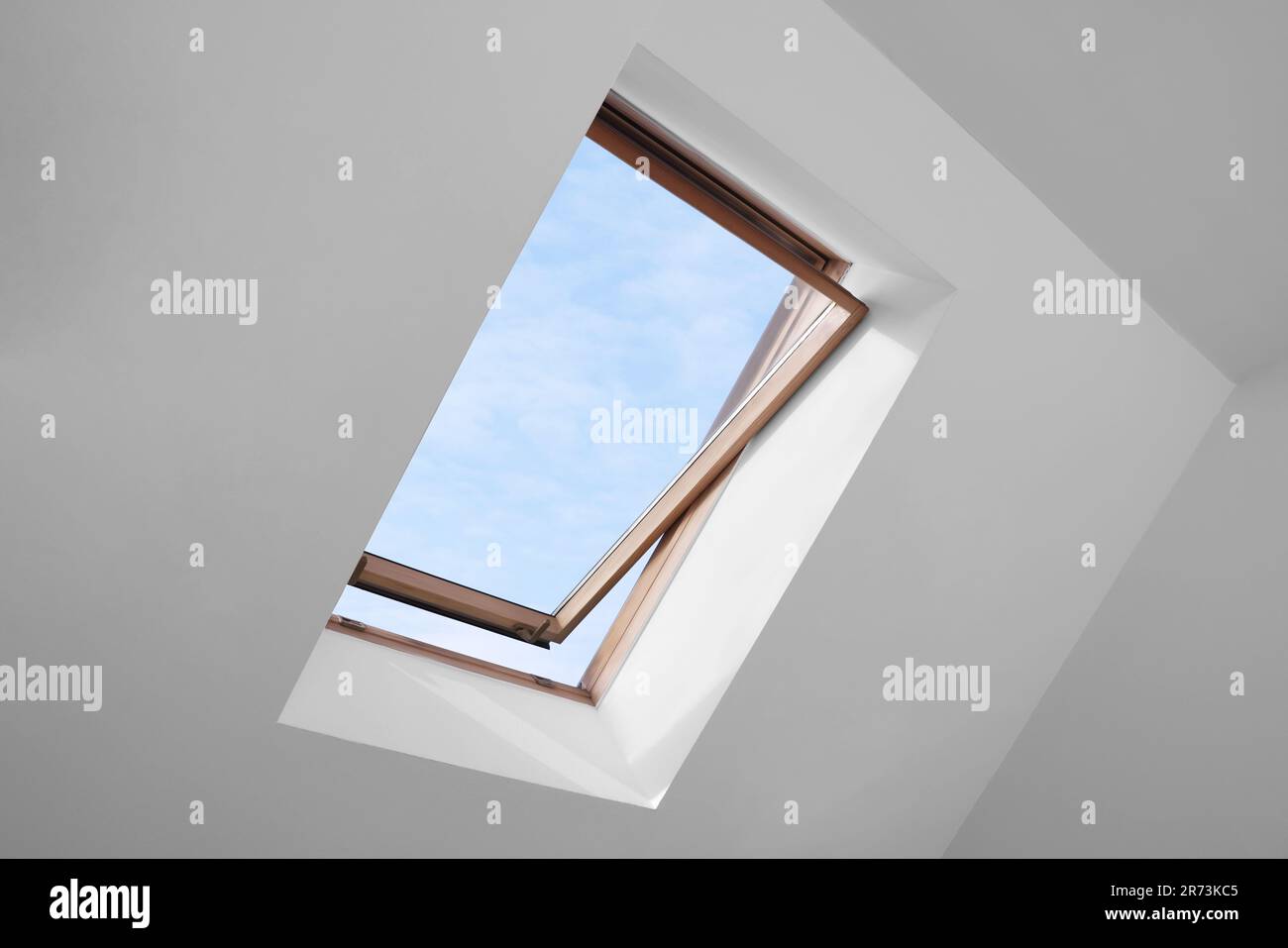 Open skylight roof window and lamps on slanted ceiling in attic room ...
