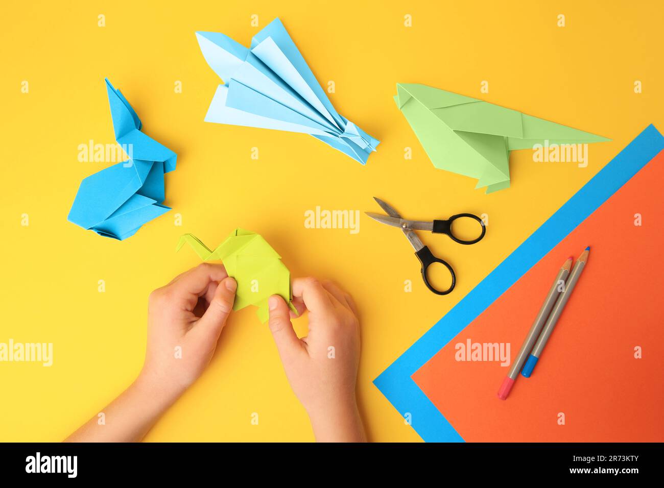 Origami art. Child holding paper figures on yellow background, closeup ...