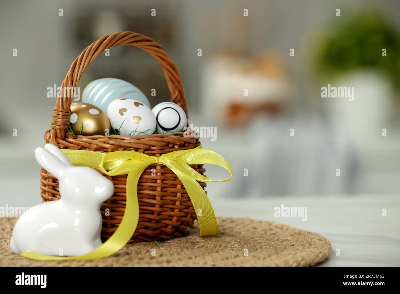Small Easter basket with painted eggs near rabbit figure on white ...