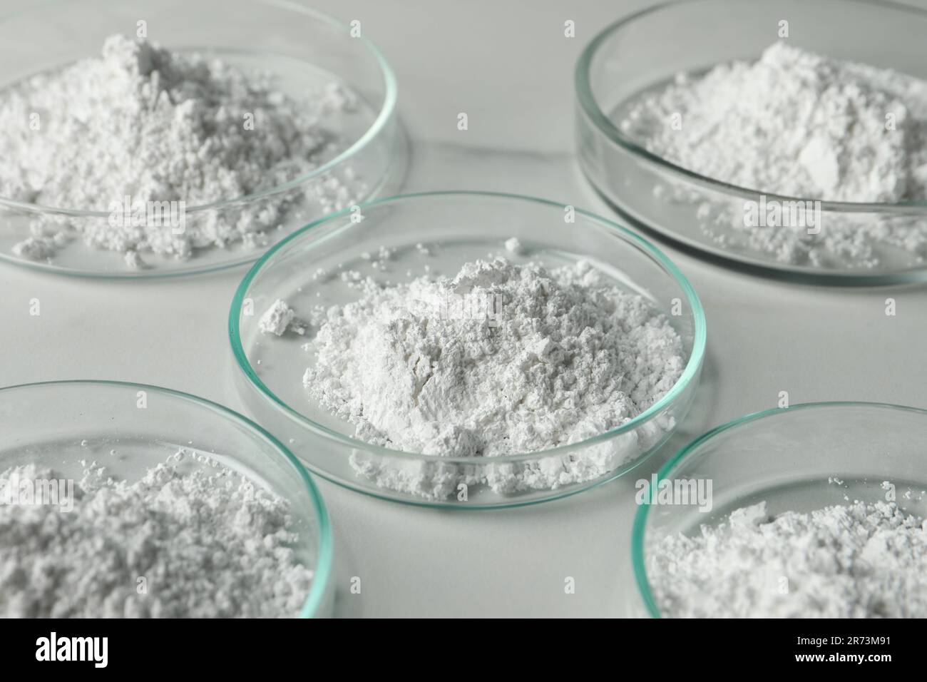 Petri dishes with calcium carbonate powder on white marble table ...