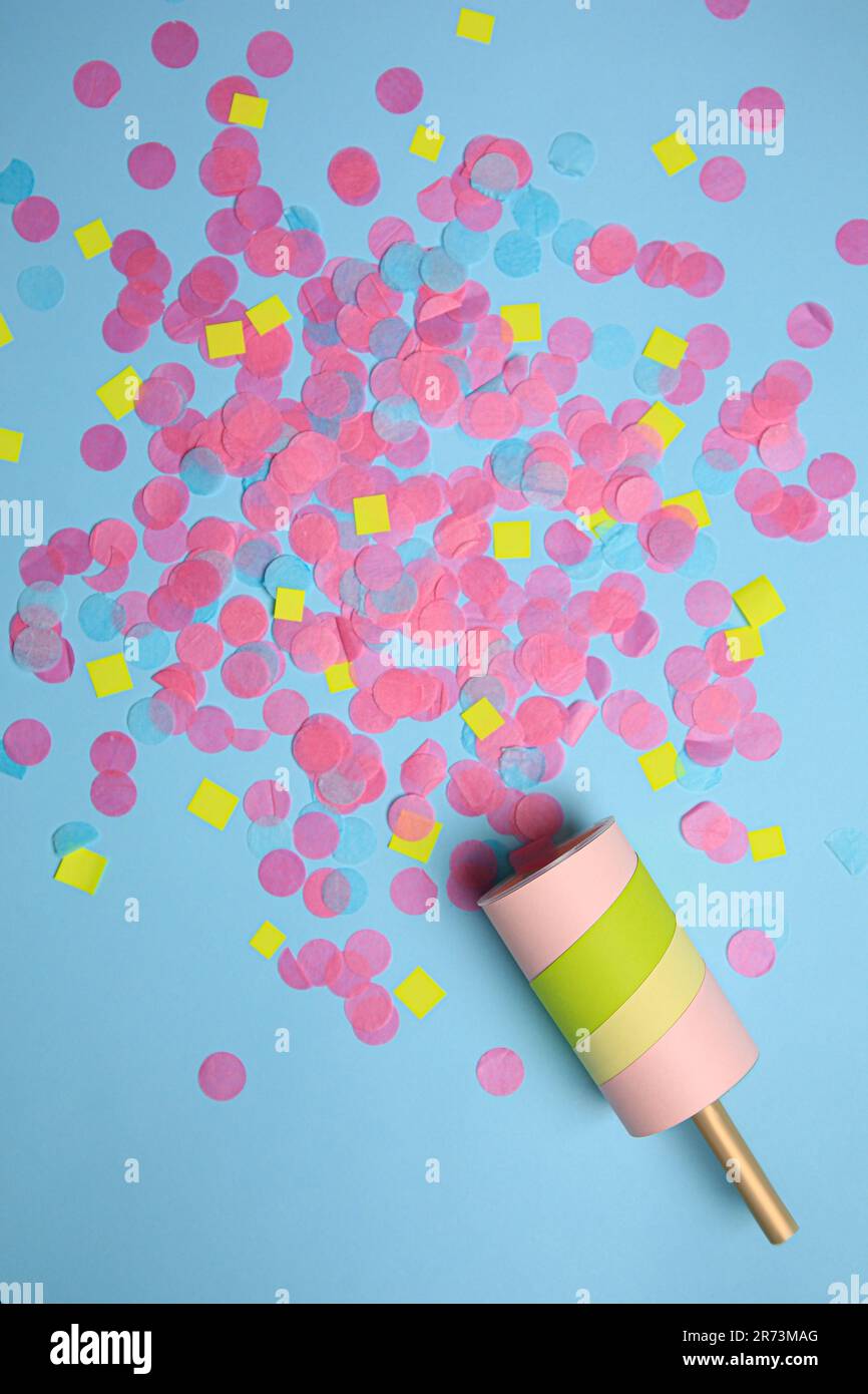 Party popper with bright confetti on light blue background, flat lay ...