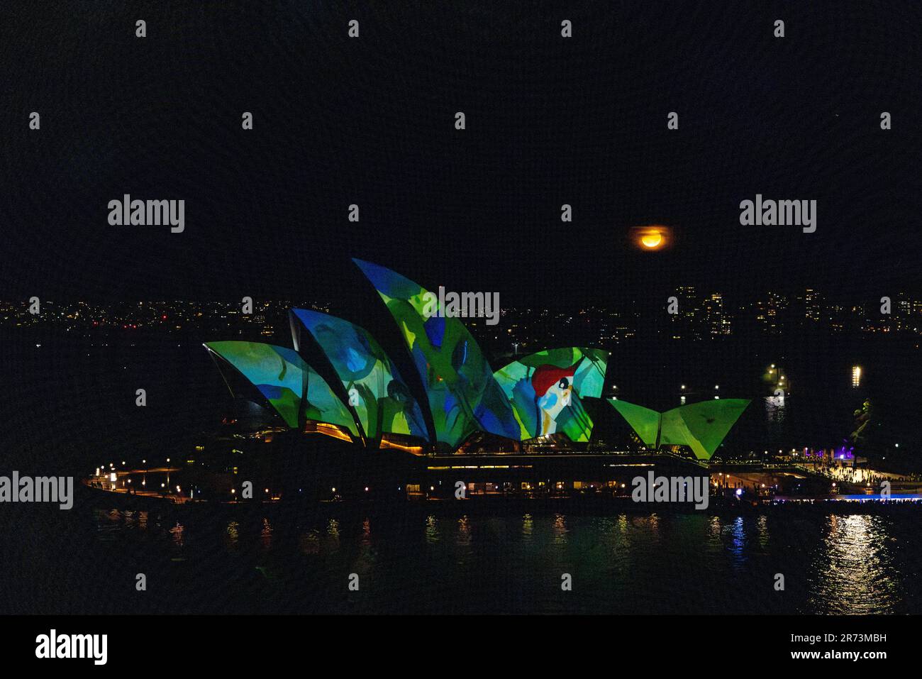 VIVID Sydney 2023. Lighting of the sails of the Opera House, Sydney Harbour. Moon rising above ...