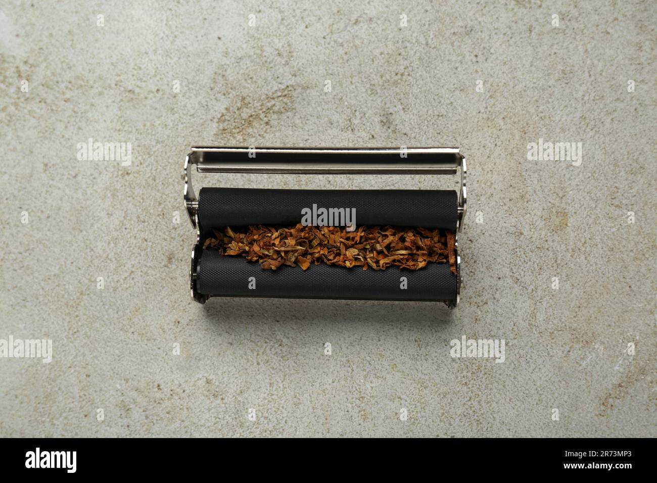 Roller with tobacco on light grey table, top view. Making hand rolled ...