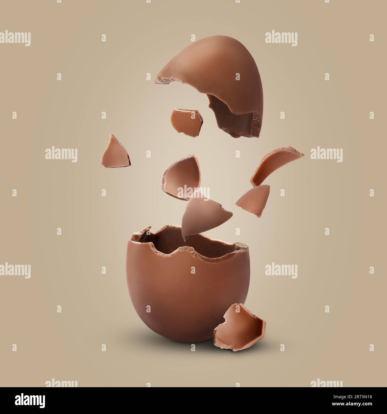 Exploded milk chocolate egg on dark beige background Stock Photo - Alamy