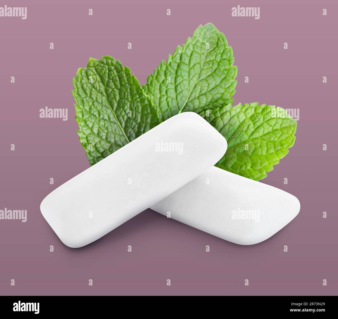 Menthol chewing gum pillows and mint leaves on dusty pink background ...