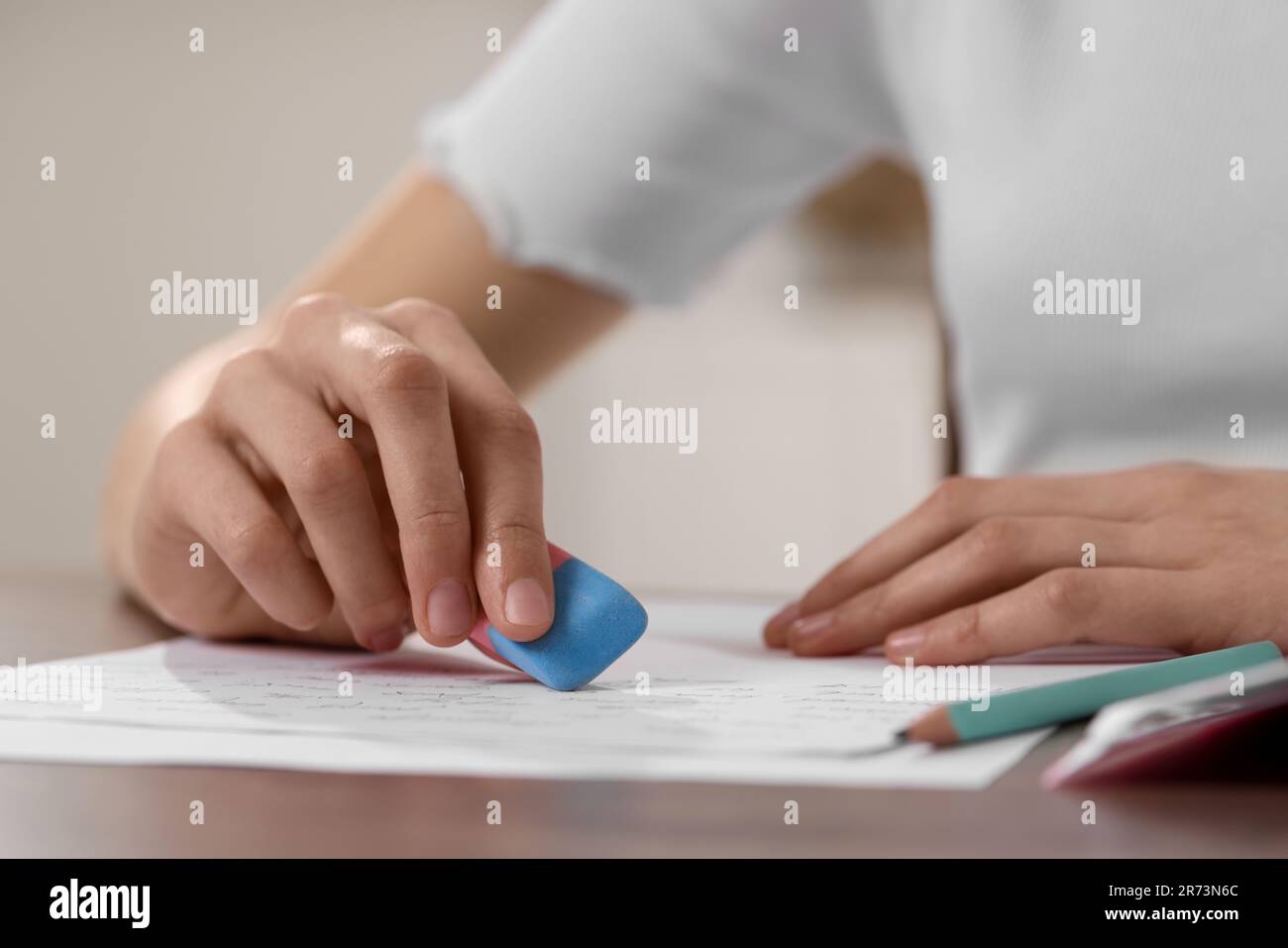 Girl erasing mistake in her notebook at wooden desk, closeup Stock ...