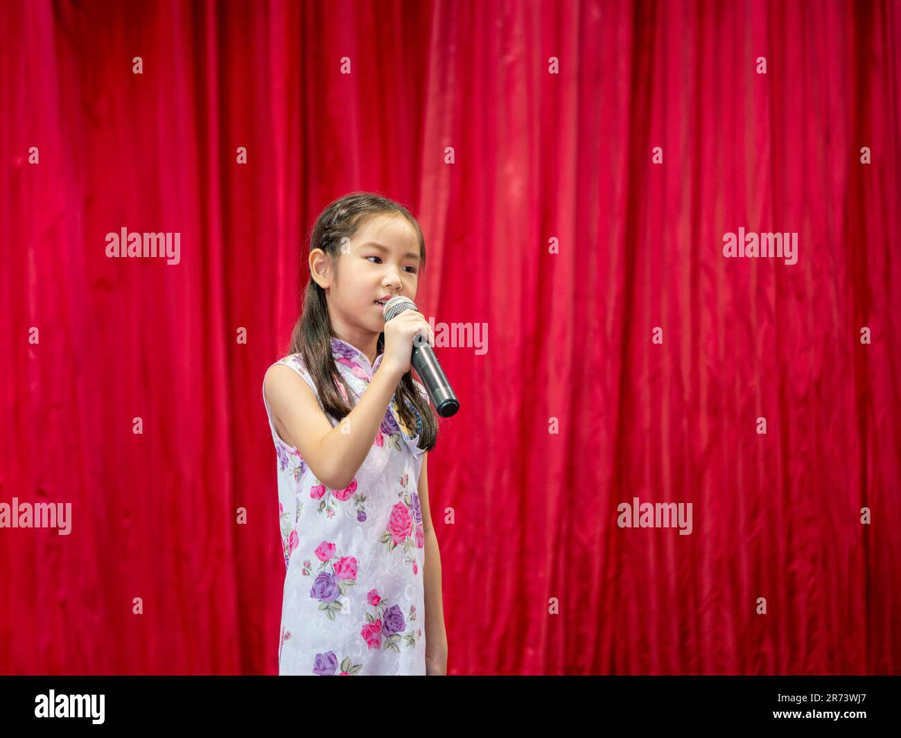 The Asian kid girl sing a song on stage at her school activity day ...