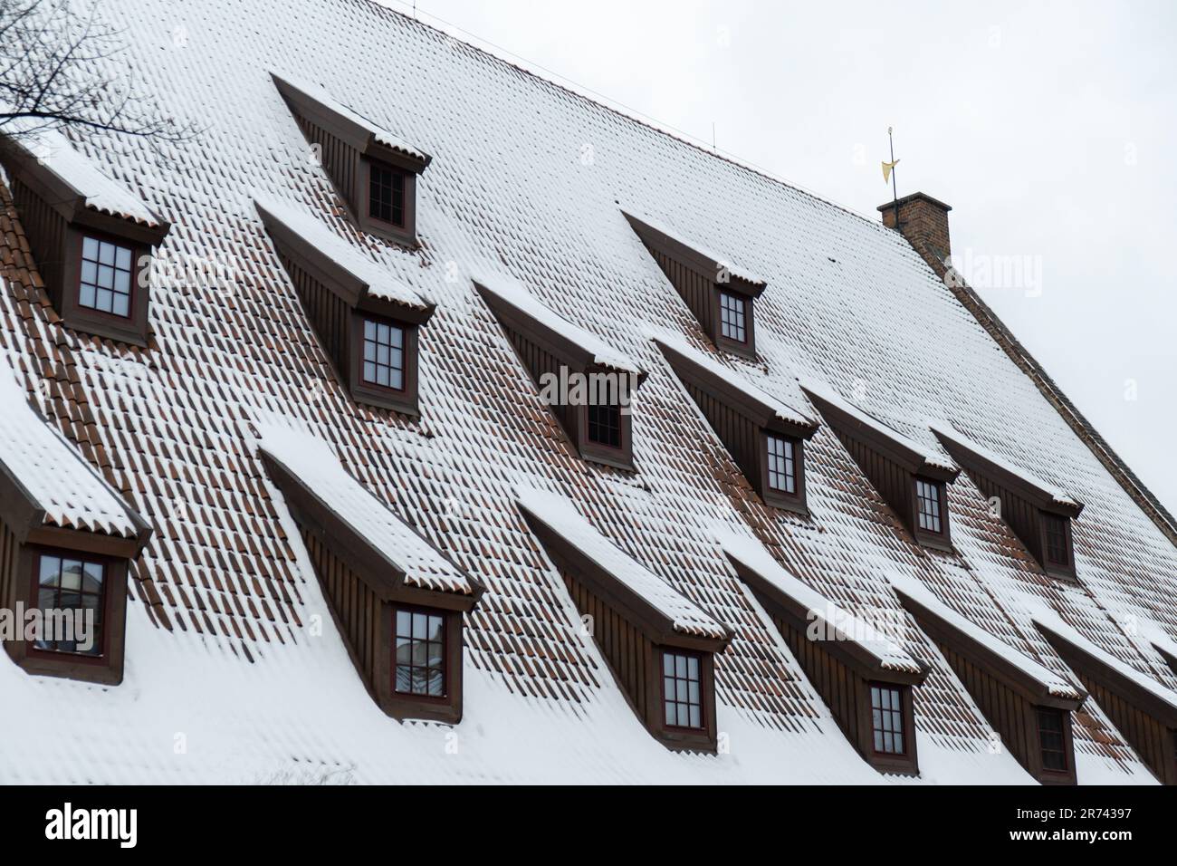 Snow falling on the roofs of the city. Snow-covered brown metal tiles ...