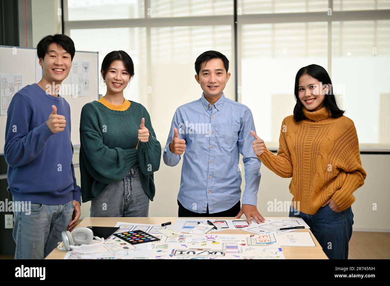 A group of cheerful Asian graphic designers or developers are showing ...